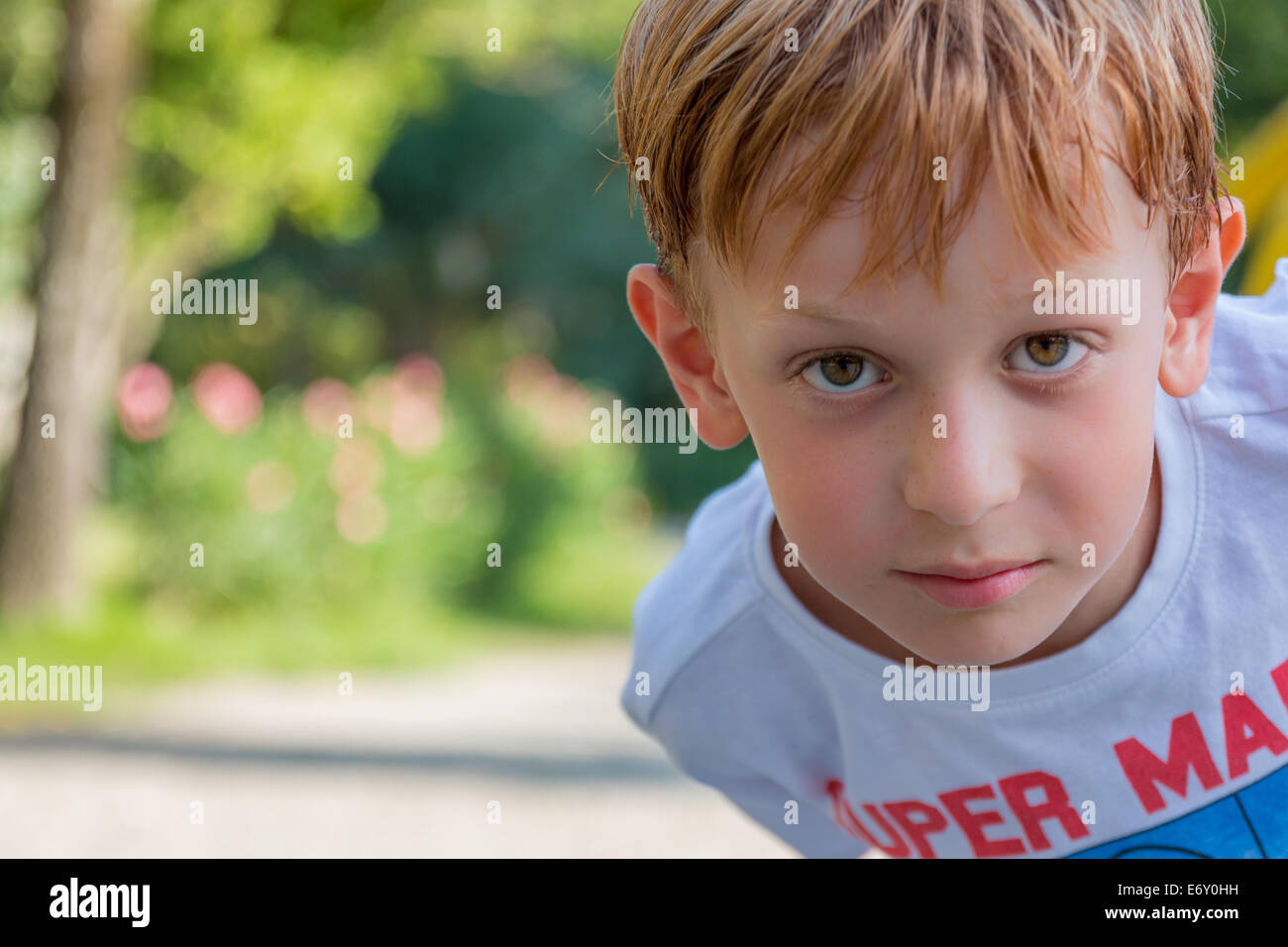 Portrait boy (7-8 years) with Red hair and white shirt at the park ...