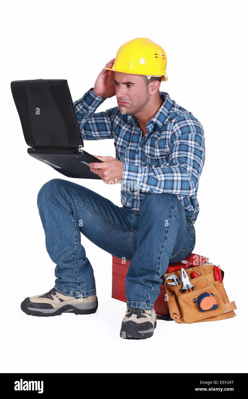 Confused builder sat with laptop Stock Photo - Alamy