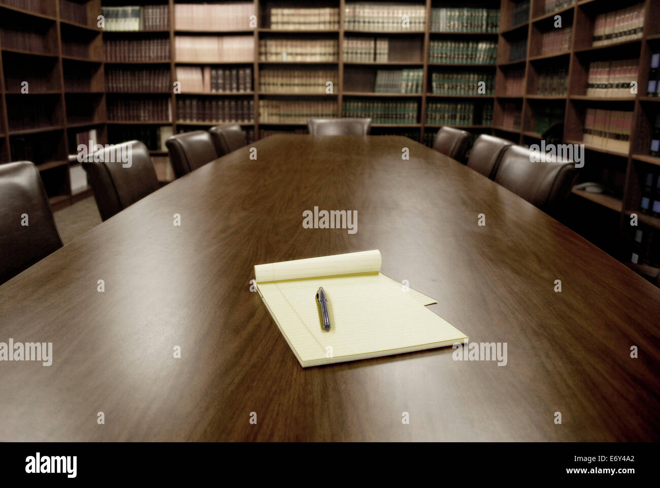 Conference room table with several leather chairs and shelves of books ...