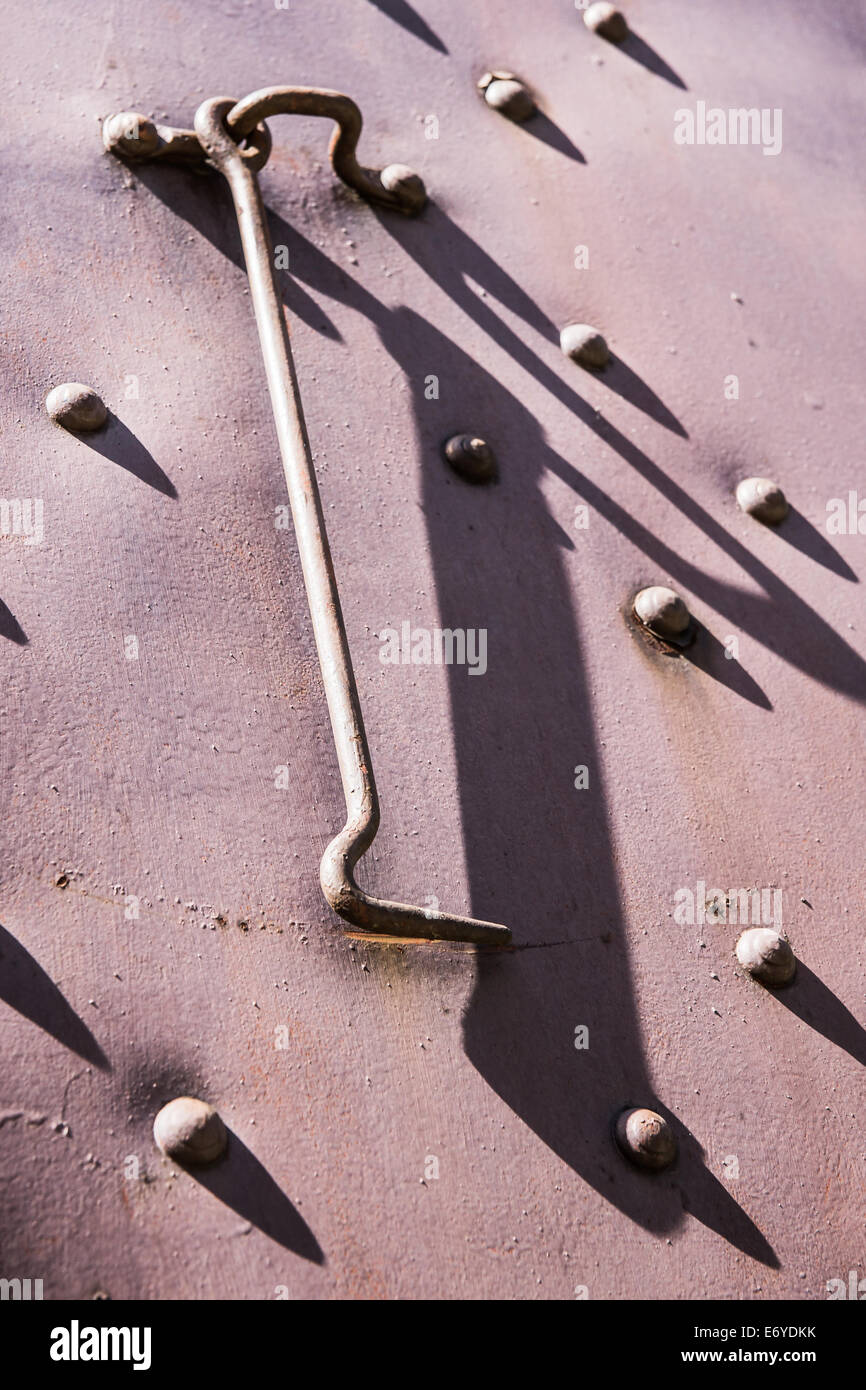 Old window shutter hook hanging vertically against the painted metallic ...