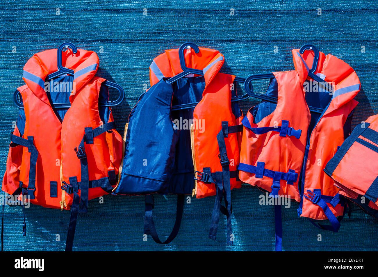 Orange color life jackets, hanging on the wall of the boating station ...