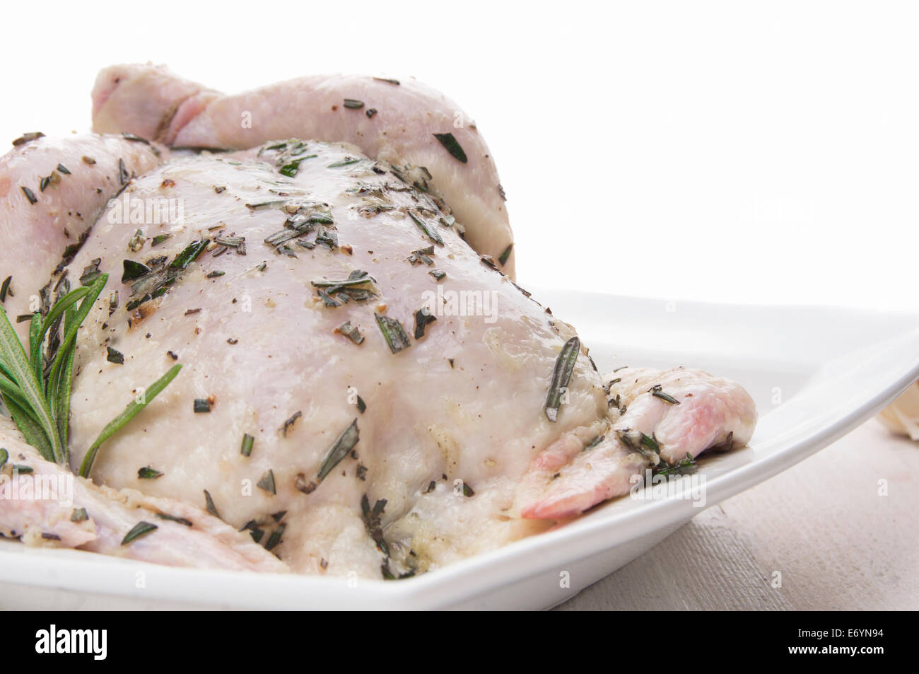 whole raw chicken with rosemary , preparation for grill roasting ,close ...