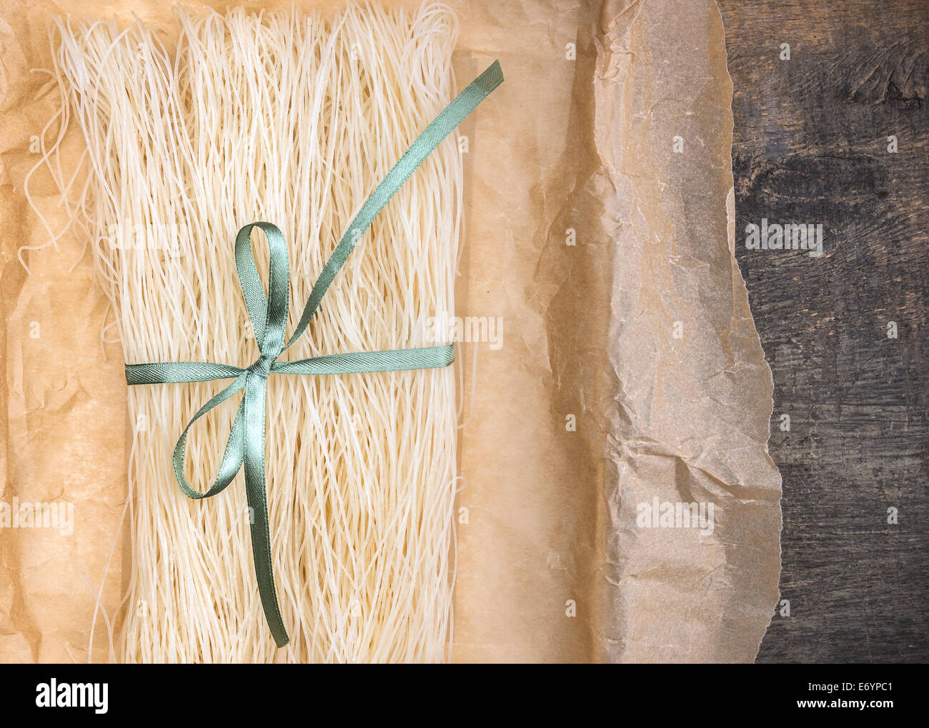 Chinese rice noodles,dry, in crumpled paper packaging with green ribbon ...