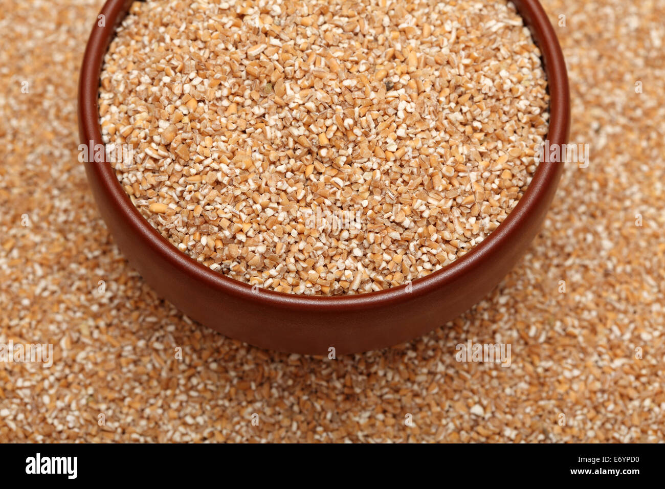 Wheat groats in bowl on wheat groats background. Closeup Stock Photo ...