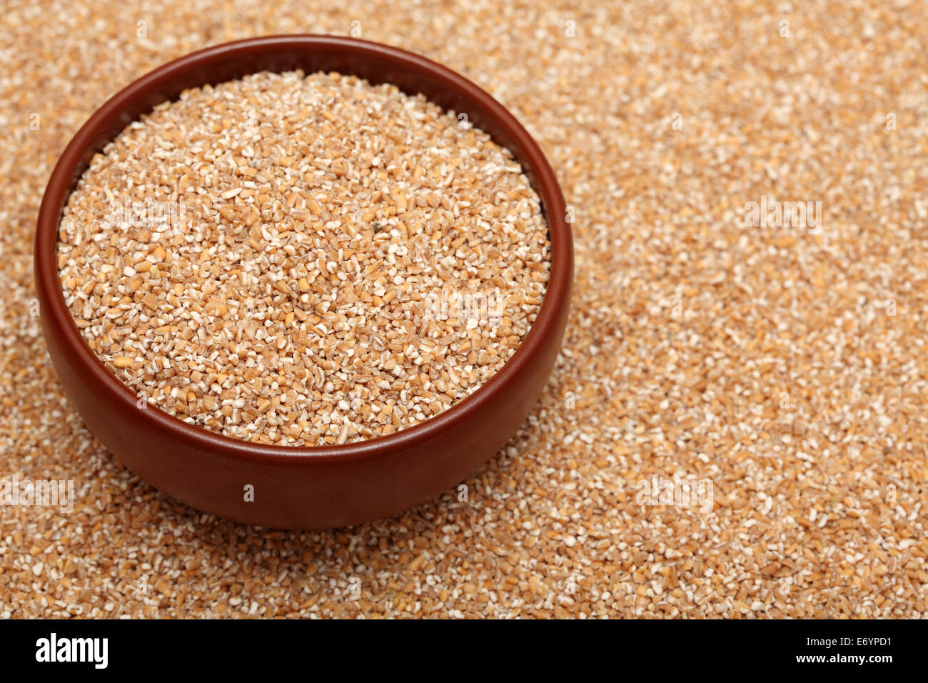 Wheat groats in bowl on wheat groats background. Closeup Stock Photo ...