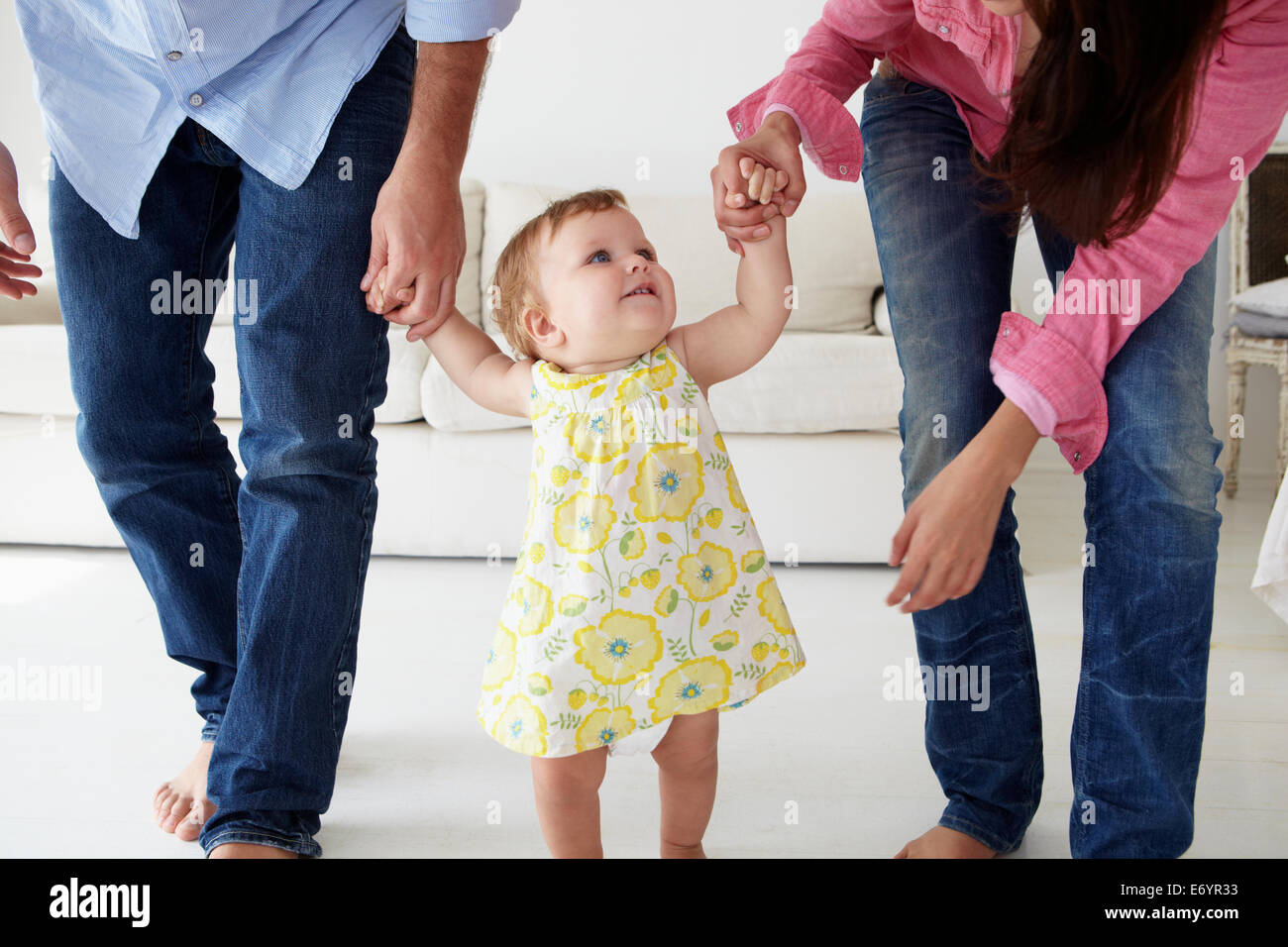 Parents teaching baby girl to walk Stock Photo - Alamy