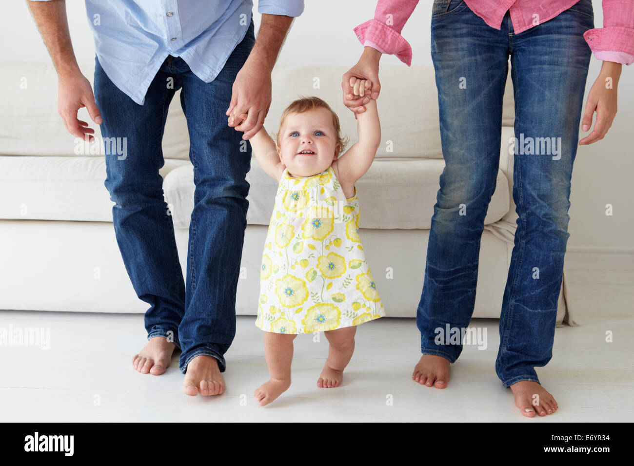 Parents teaching baby girl to walk Stock Photo - Alamy
