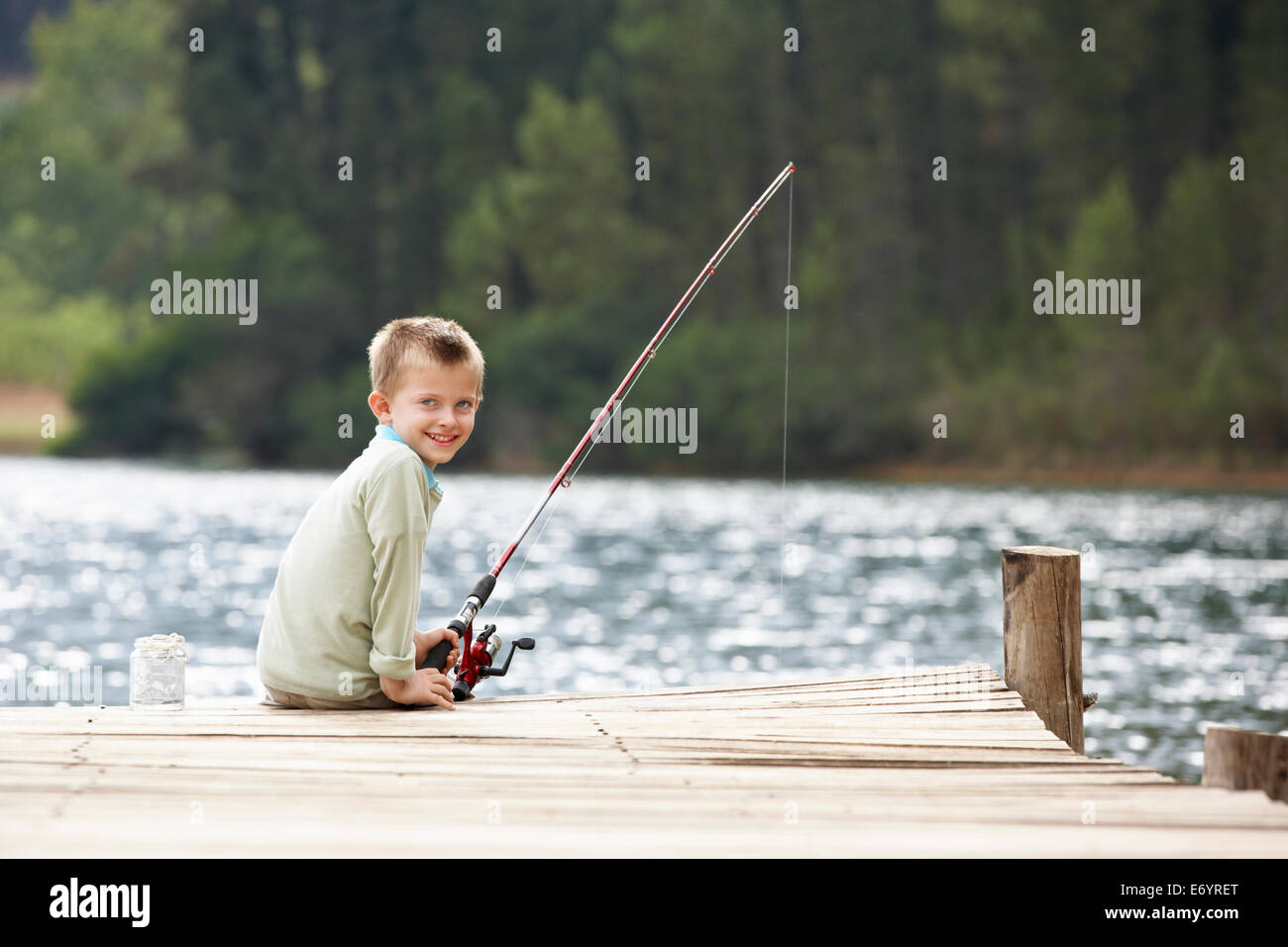 Young boy fishing on a jetty Stock Photo - Alamy