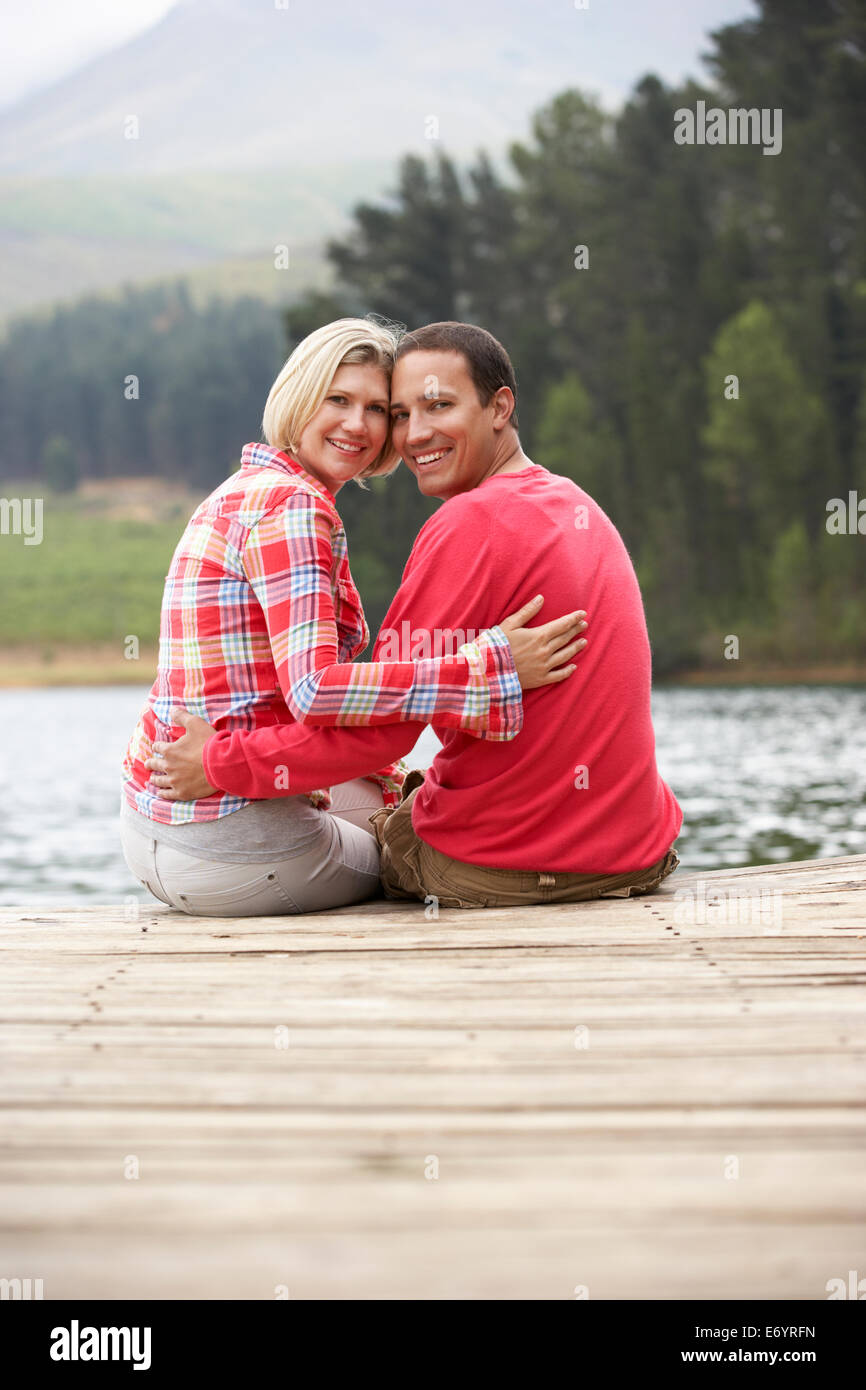 Romantic couple sitting on a jetty Stock Photo - Alamy