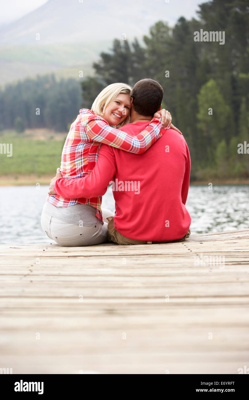 Romantic couple sitting on a jetty Stock Photo - Alamy