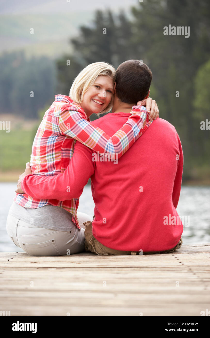 Romantic couple sitting on a jetty Stock Photo - Alamy