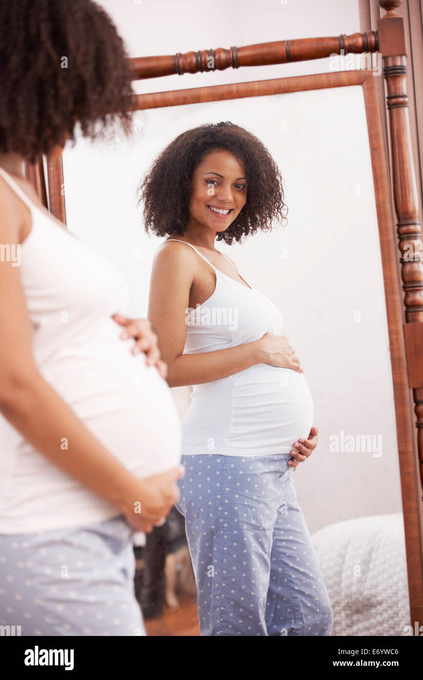 Pregnant woman looking in mirror Stock Photo - Alamy