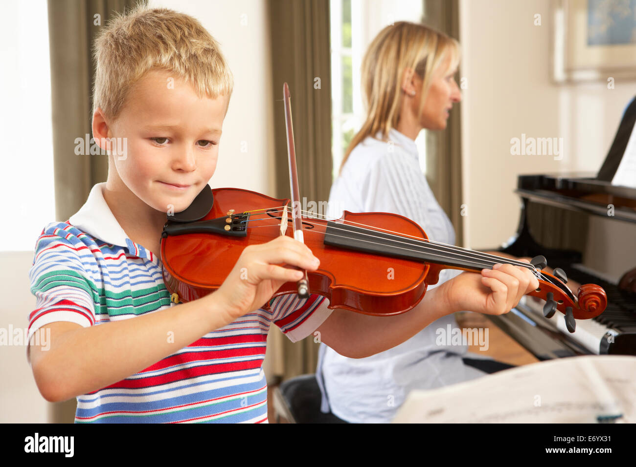Young boy playing violin accompanied by teacher Stock Photo - Alamy