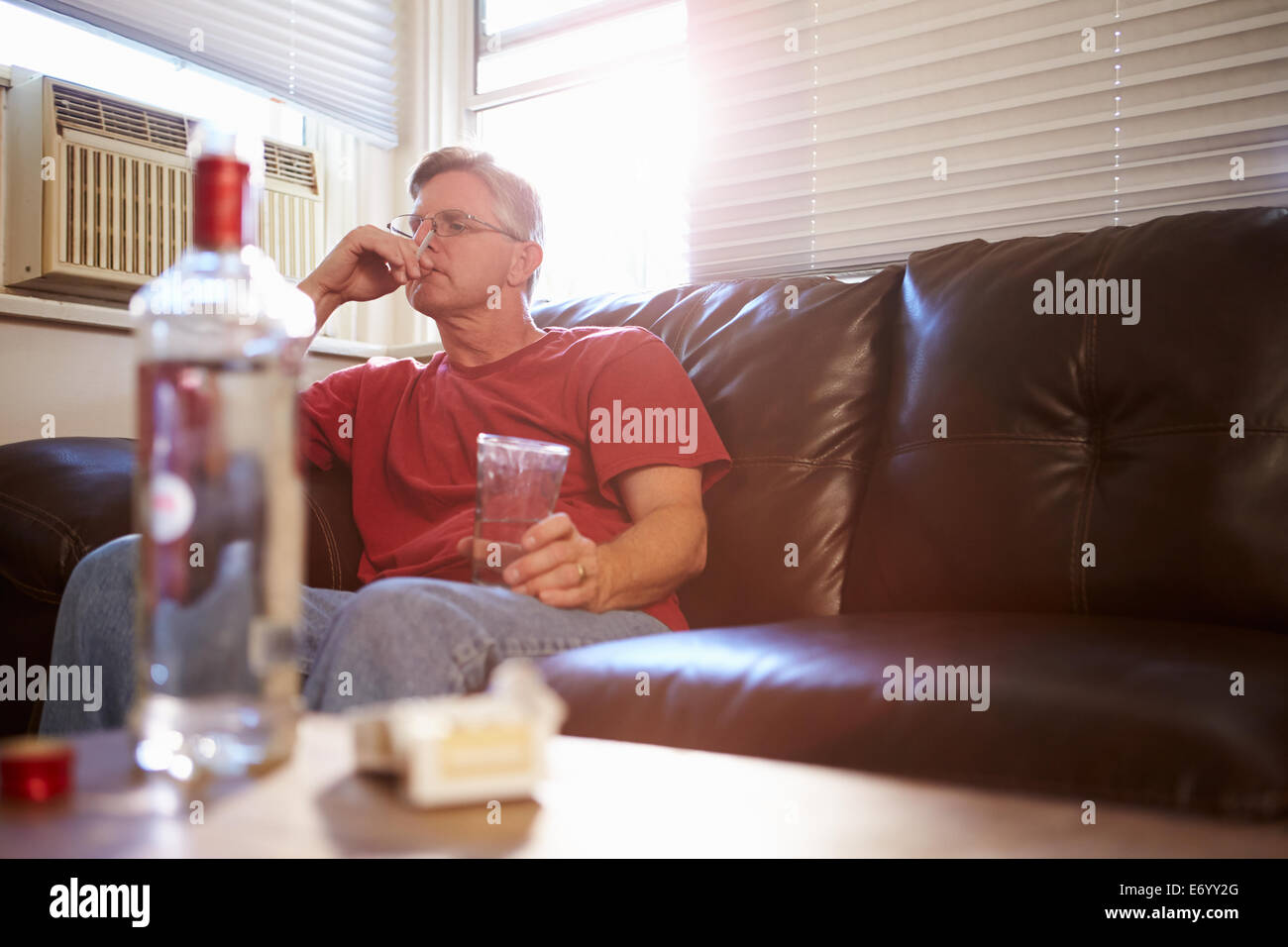 Man Sitting On Sofa With Bottle Of Vodka And Cigarettes Stock Photo - Alamy