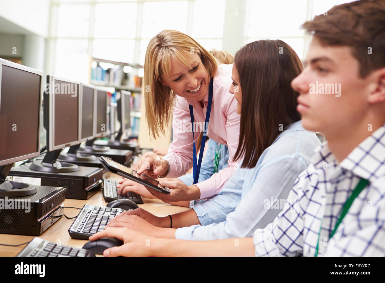 Students Working At Computers In Library With Teacher Stock Photo - Alamy