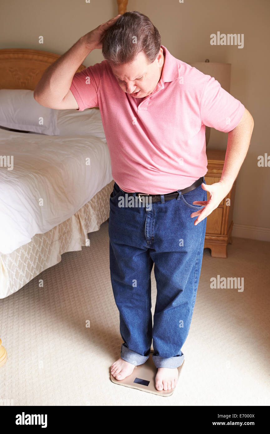 Overweight Man Weighing Himself On Scales In Bedroom Stock Photo - Alamy