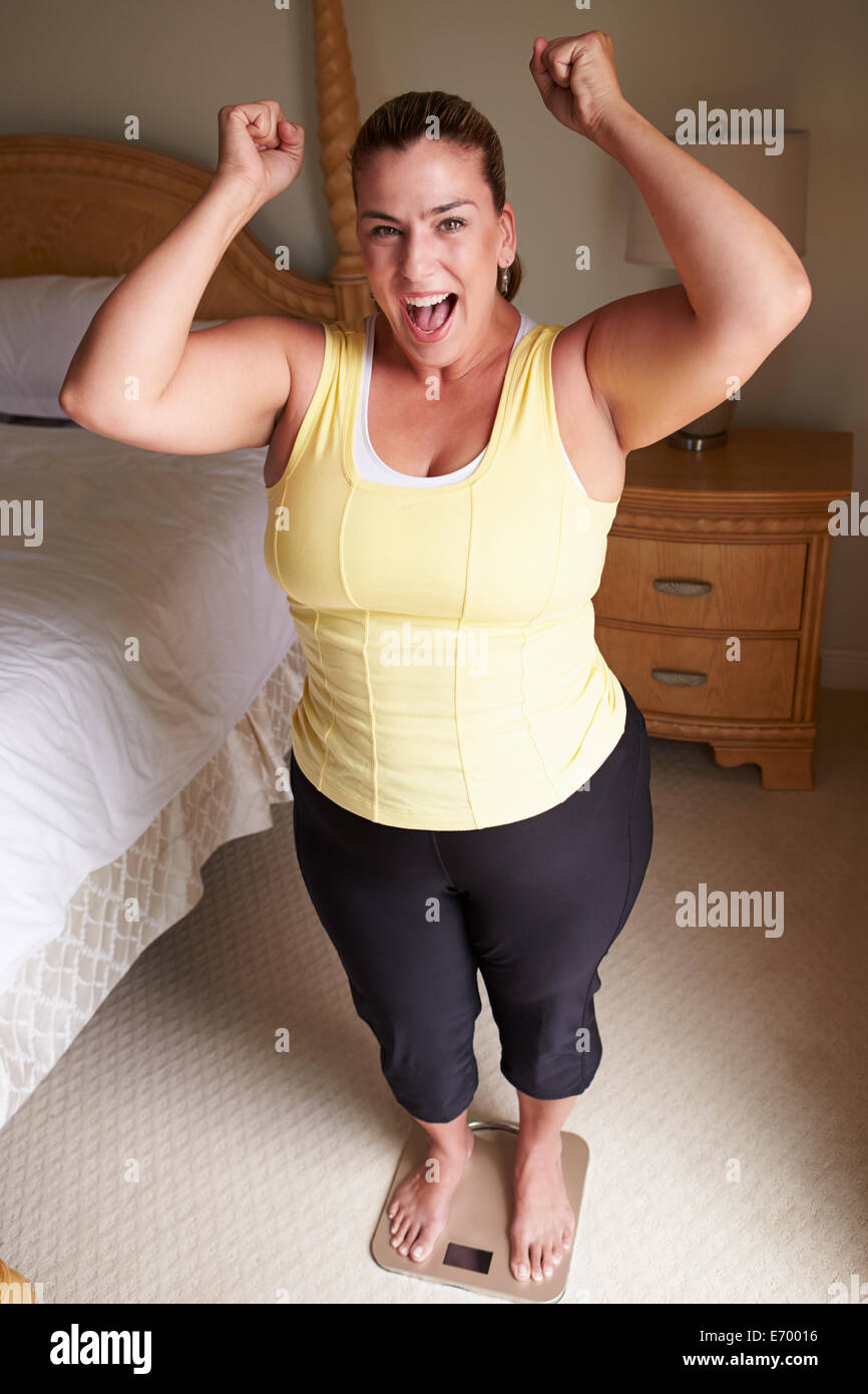 Overweight Woman Weighing Herself On Scales In Bedroom Stock Photo - Alamy