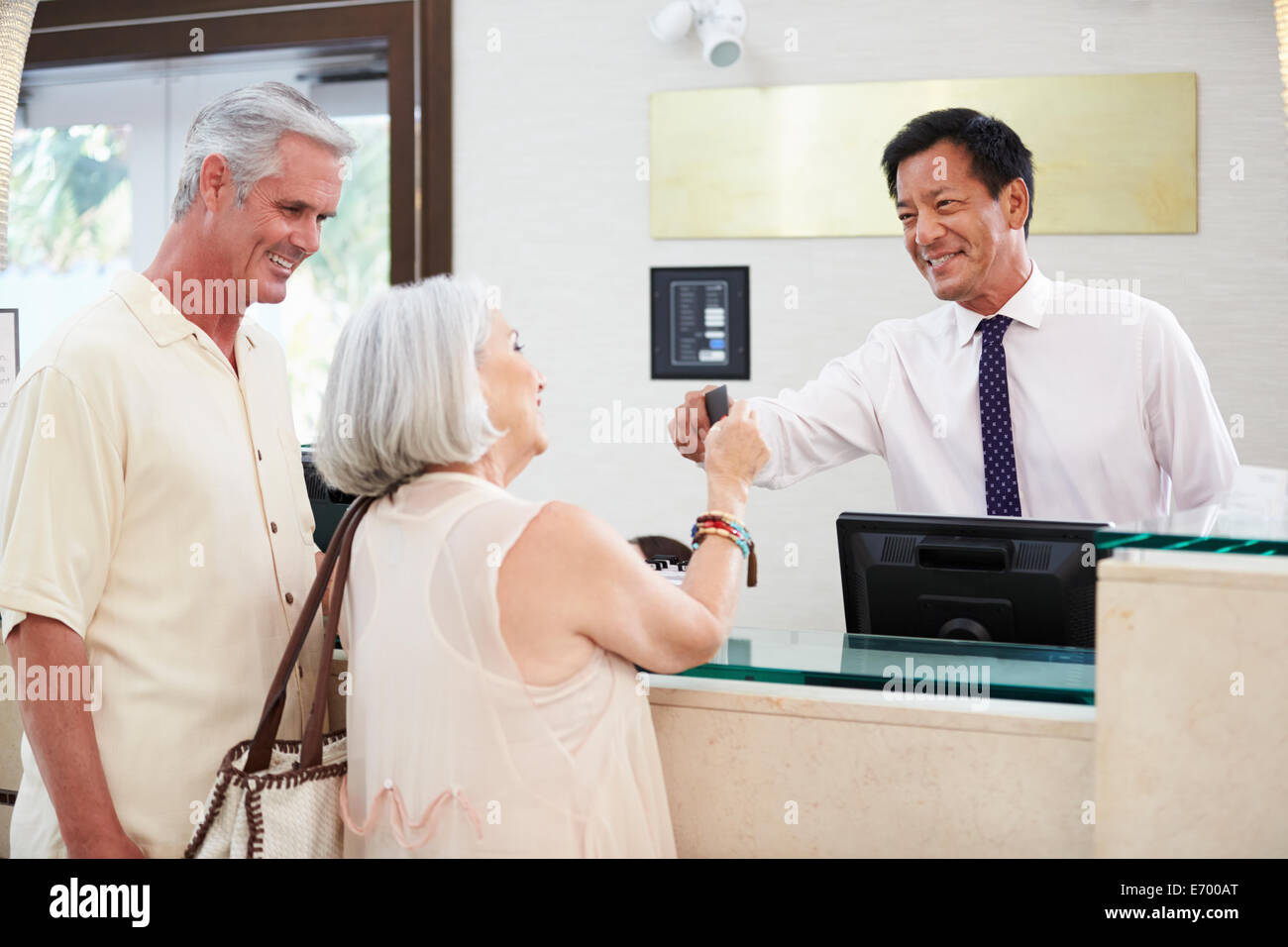 Senior Couple Checking In At Hotel Reception Stock Photo - Alamy