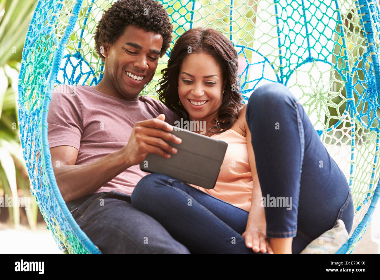 Couple On Outdoor Garden Swing Seat Using Digital Tablet Stock Photo ...