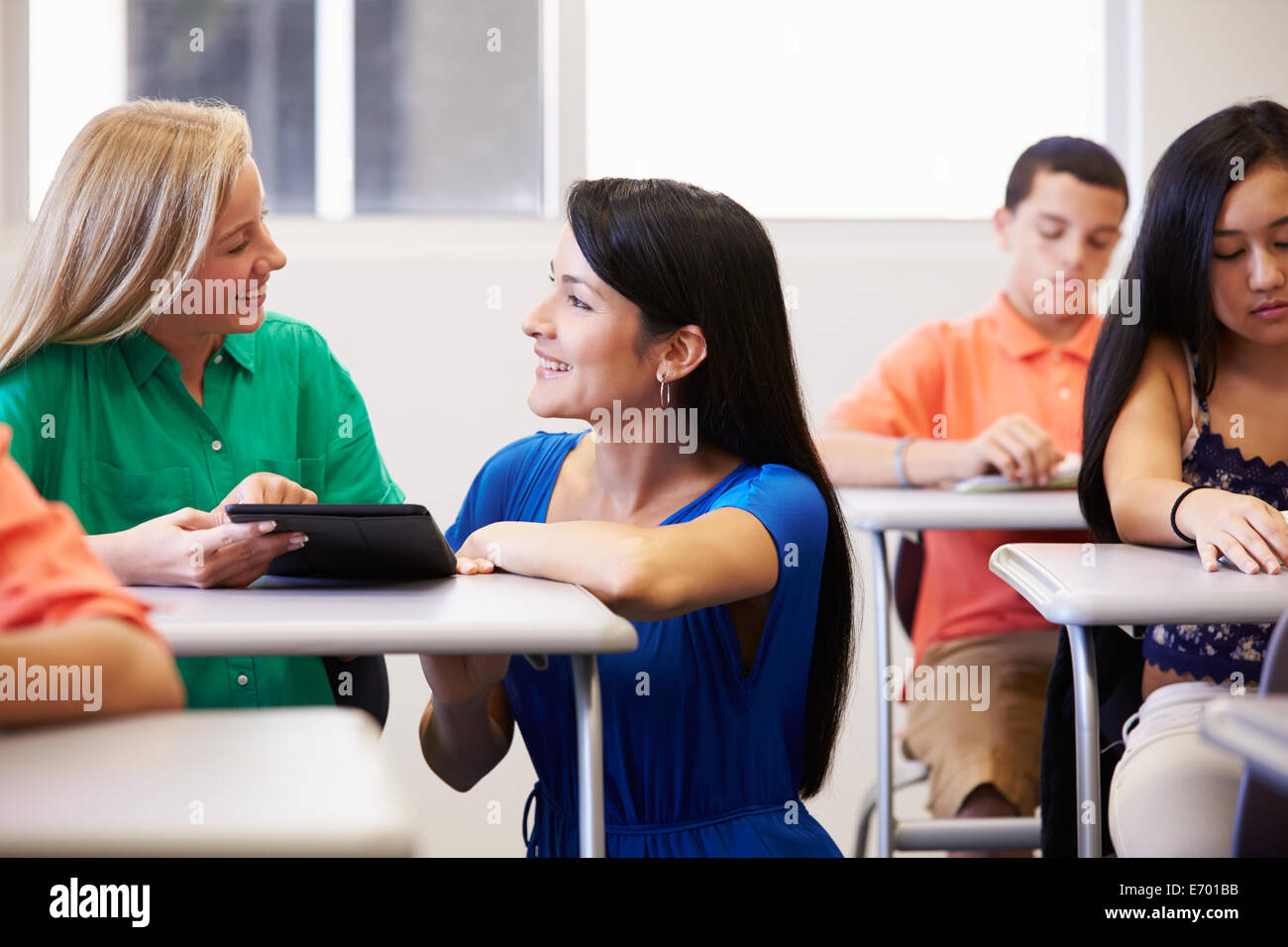 Teacher Helping Female High School Student In Classroom Stock Photo - Alamy