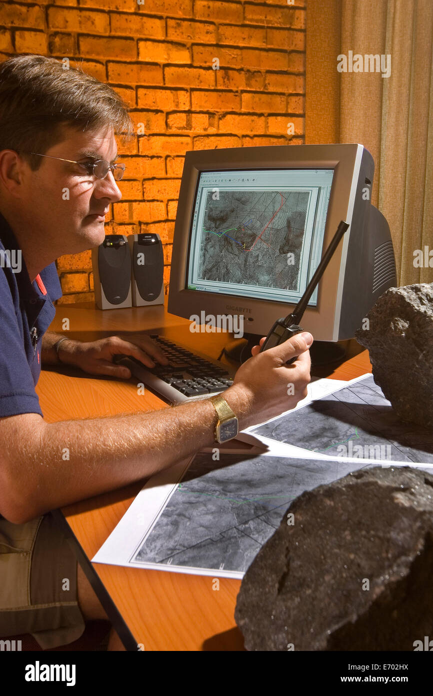 Geologist holding radio telephone while working on geotek surface and ...