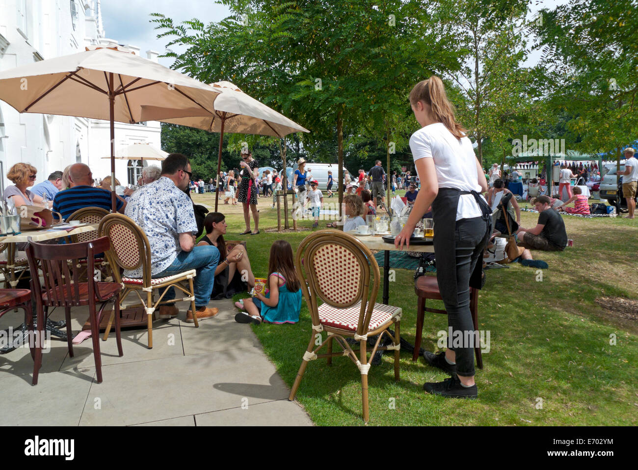 People having tea and waitress clearing tables in the garden at ...