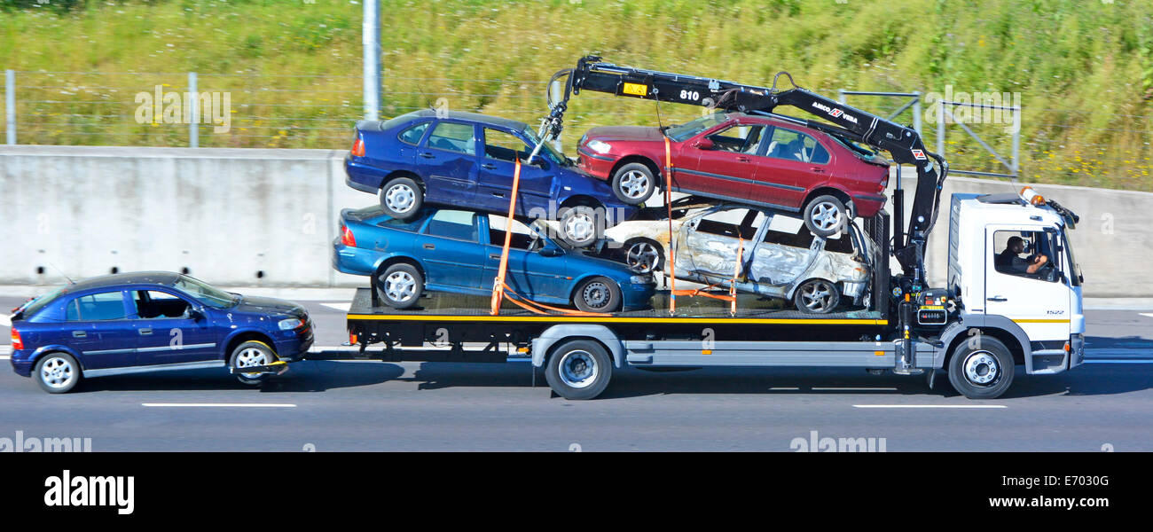 Five damaged cars being transported by flat bed lorry along a UK ...