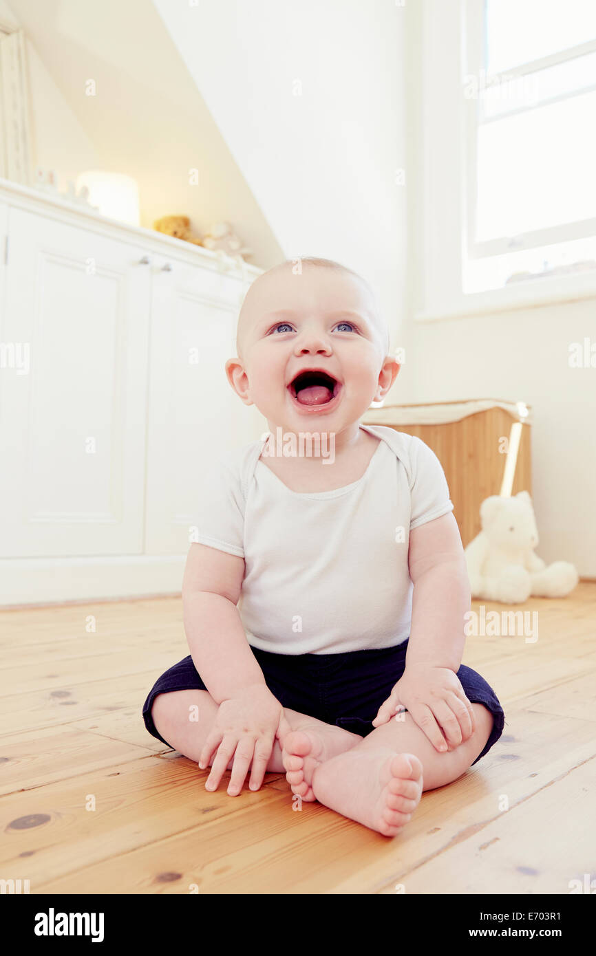 Portrait of smiling baby boy sitting on floor Stock Photo - Alamy