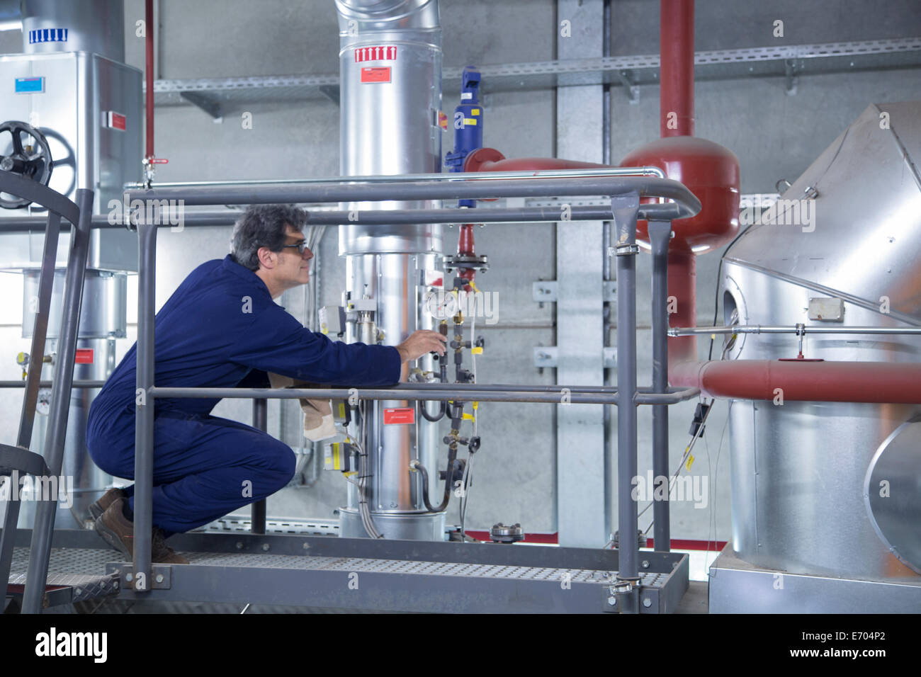 Engineer inspecting equipment from access platform in power station ...