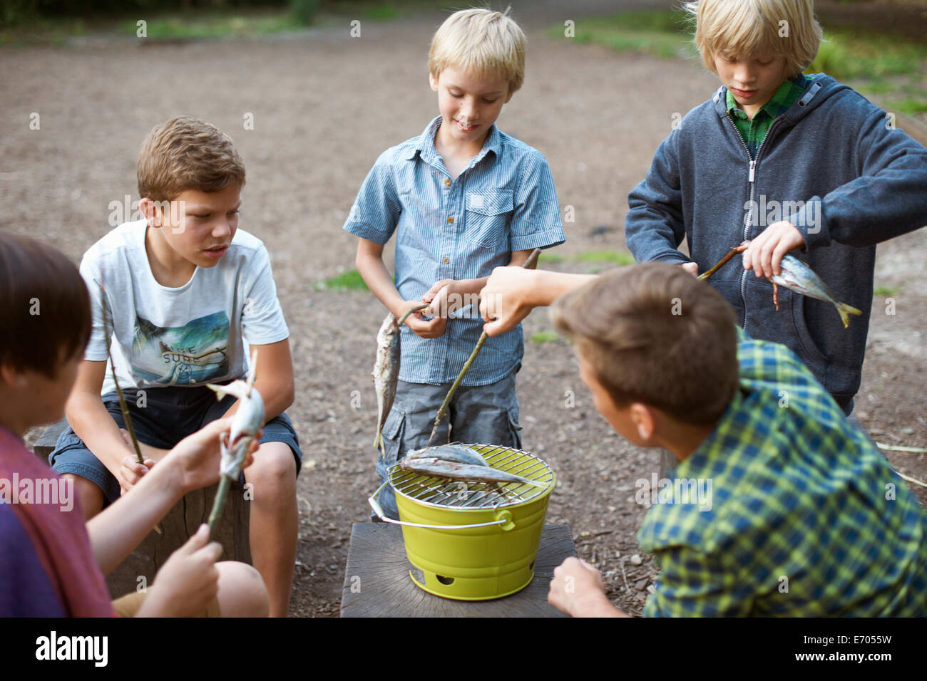 Young boys cooking fish over barbecue Stock Photo - Alamy