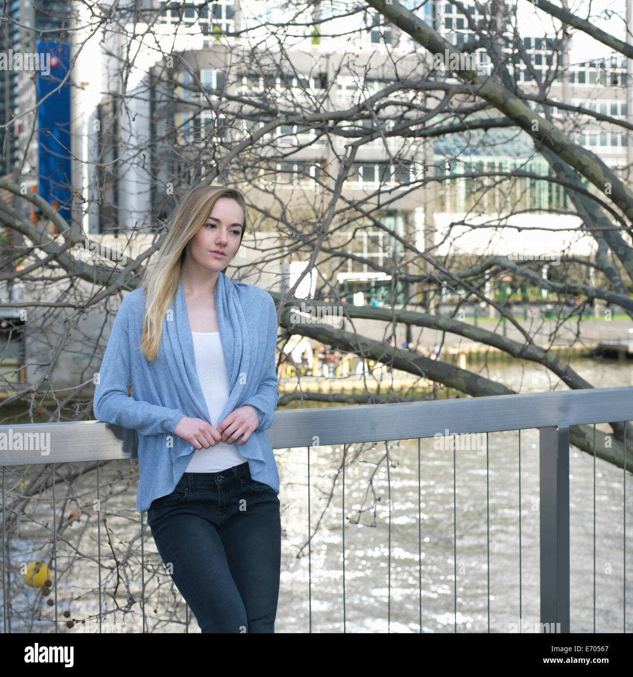 Young woman leaning against railings at city riverside Stock Photo - Alamy