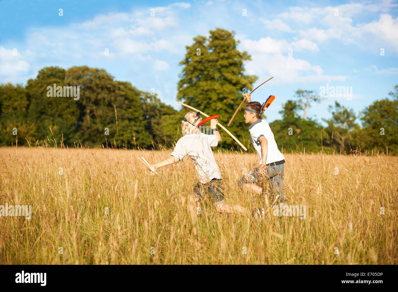 Two young boys running with bow and arrow Stock Photo - Alamy