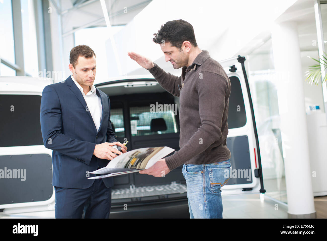 Customer questioning salesman in car dealership Stock Photo - Alamy