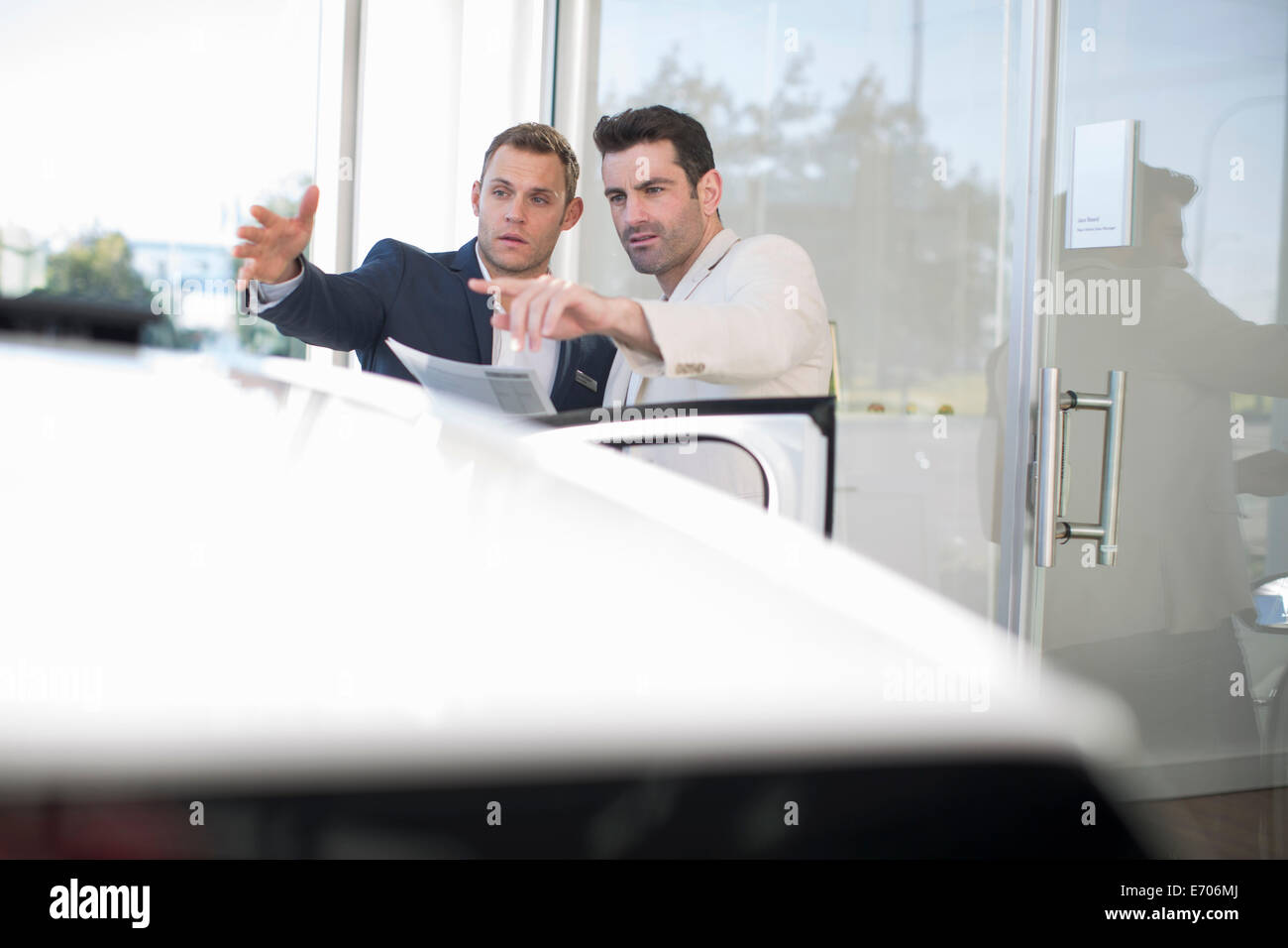 Customer questioning salesman in car dealership Stock Photo - Alamy