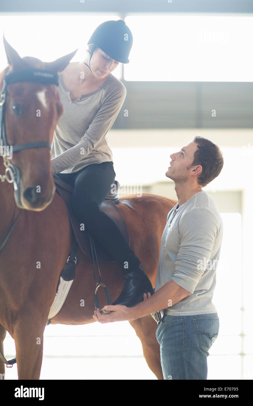 Female horseback rider with instructor in indoor paddock Stock Photo ...