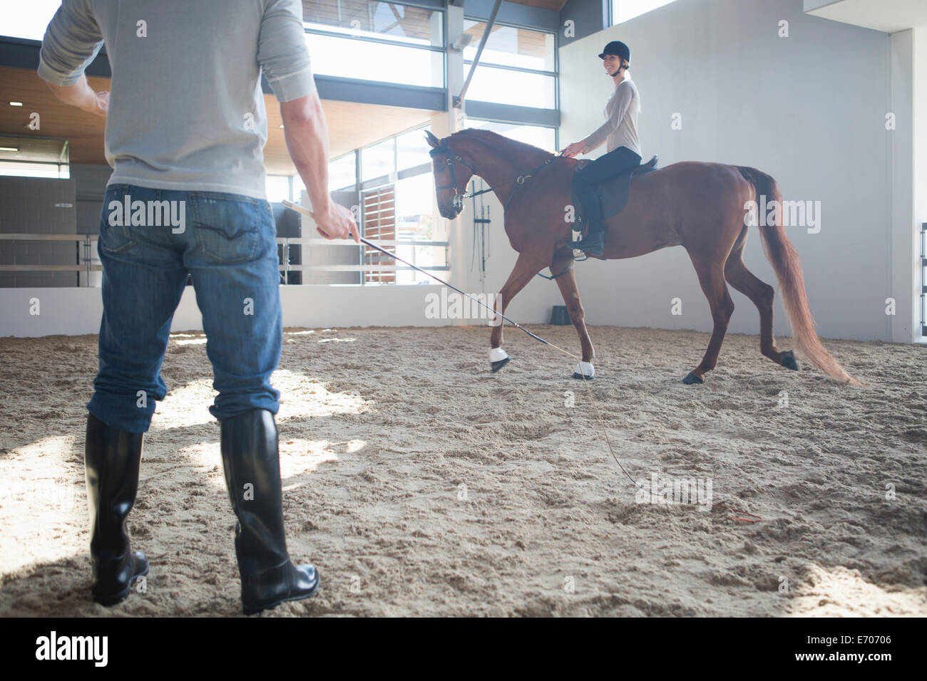 Female horseback riding with instructor in indoor paddock Stock Photo ...