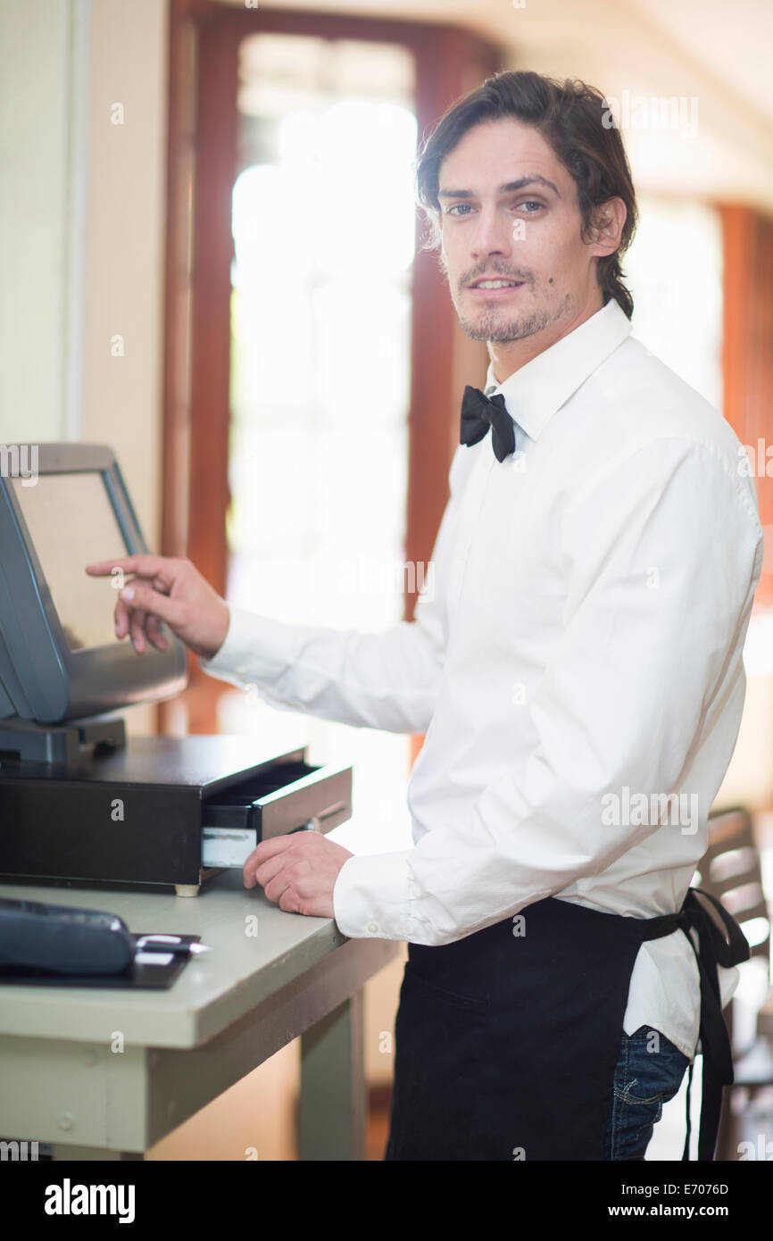 Portrait of waiter using touch screen on cash register in restaurant ...