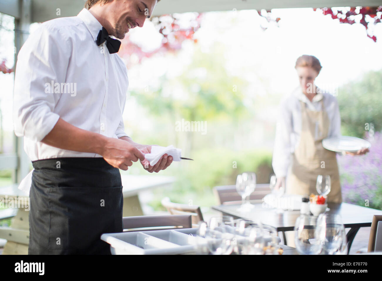 Waiter polishing cutlery with napkin in patio restaurant Stock Photo ...