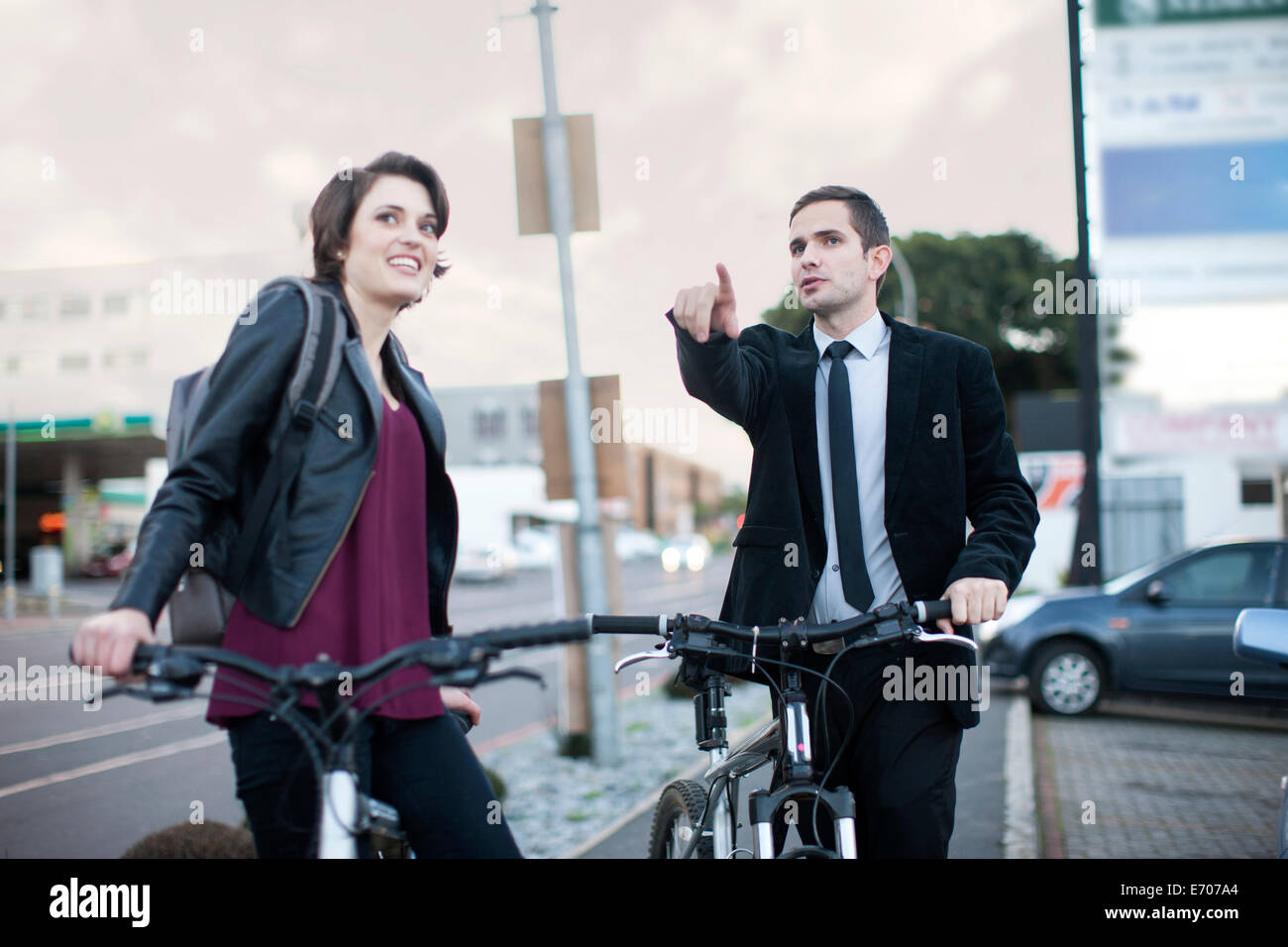 Young woman taking directions from businessman whilst cycling in city ...