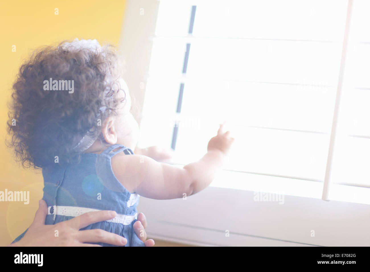 Mother holding baby daughter up to window Stock Photo - Alamy