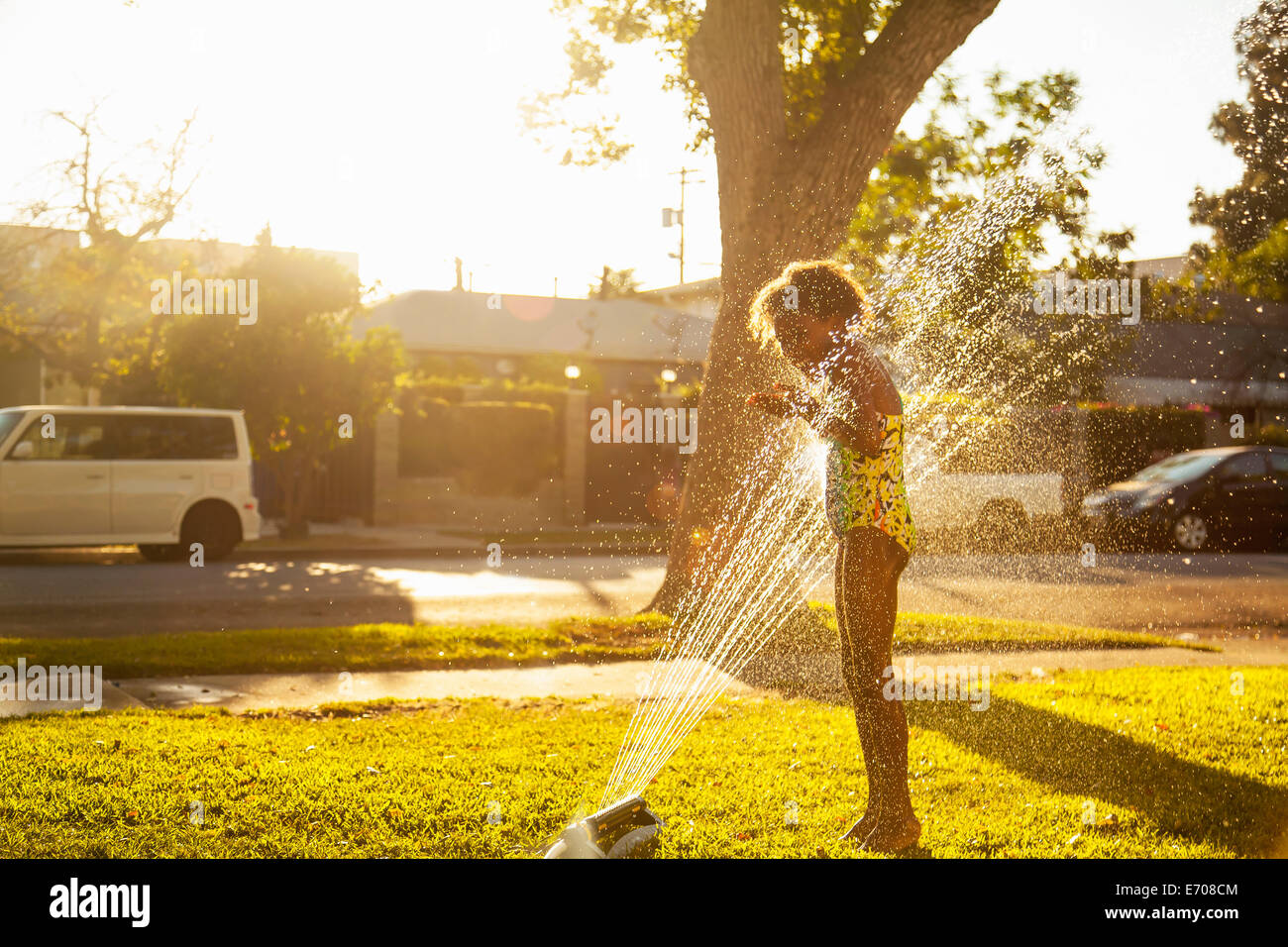 Girl standing in garden sprinkler Stock Photo - Alamy