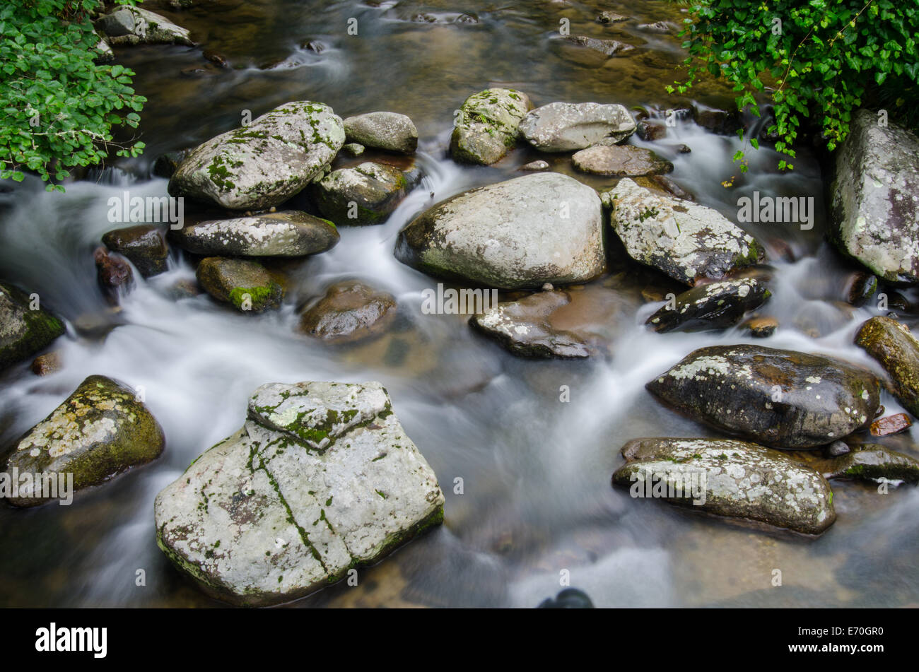 Water cascading over rocks in a creek is captured with a long exposure ...