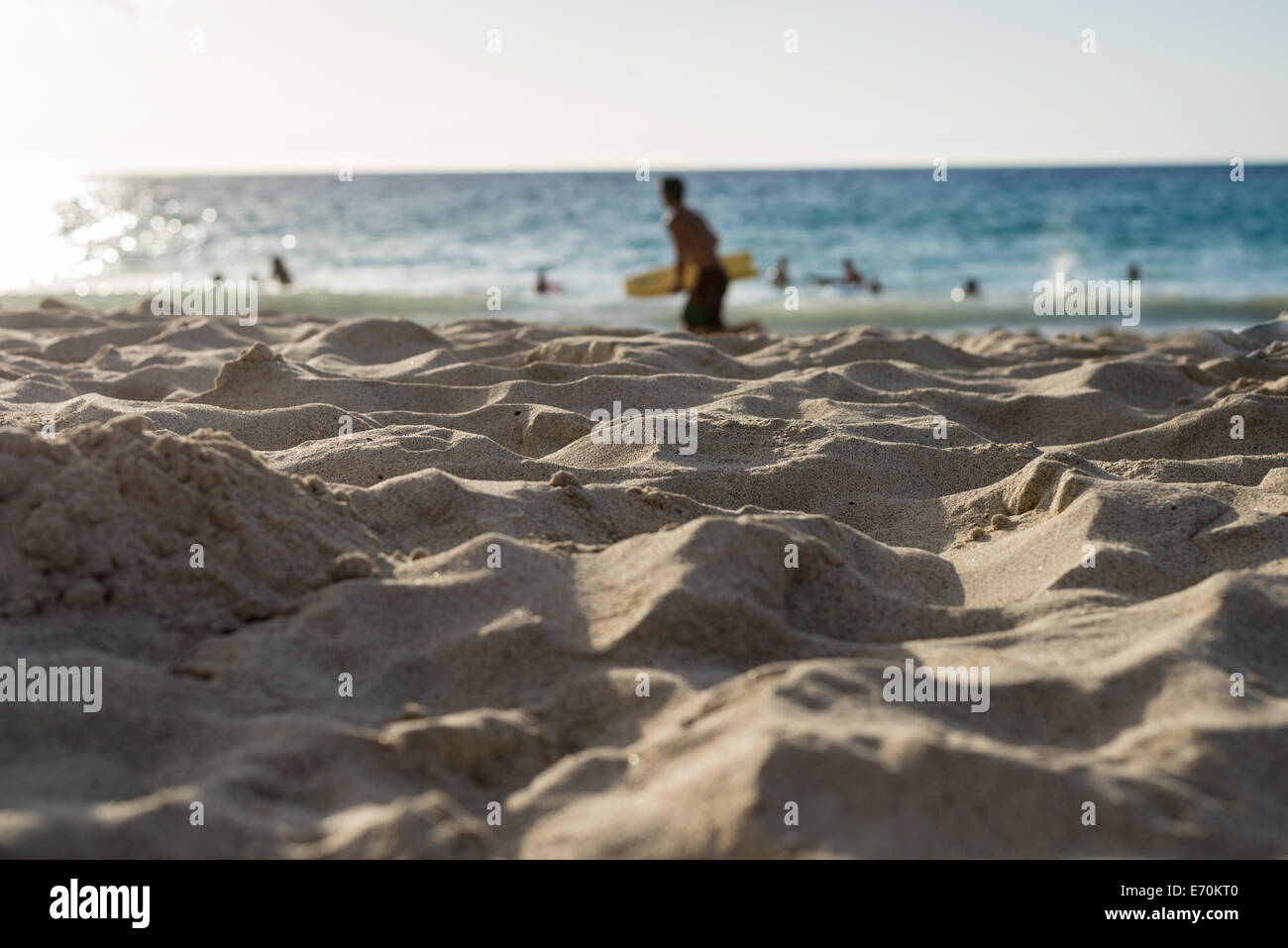 sand close-up at beach near blue ocean where people are swimming and ...