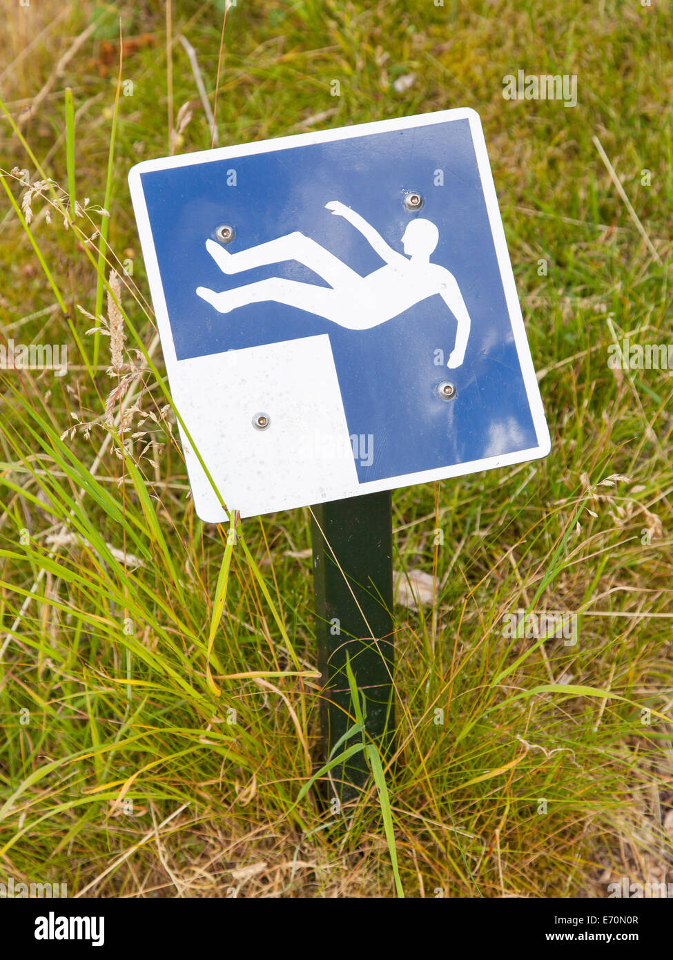 Blue falling hazard sign standing in the grass Stock Photo - Alamy