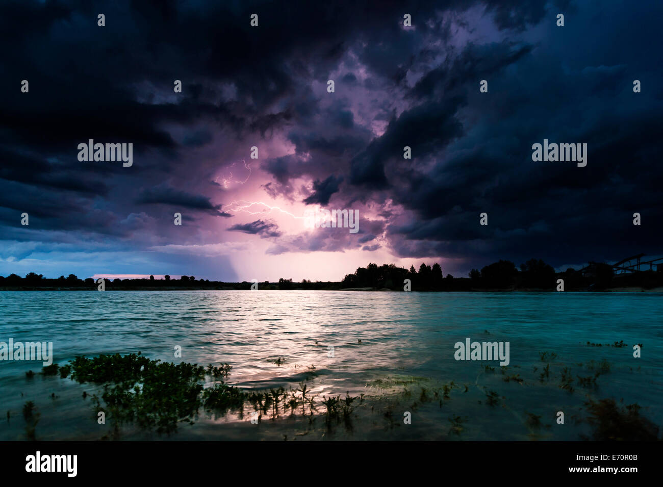 Storm clouds over a quarry lake with water plants, near Mindelheim ...