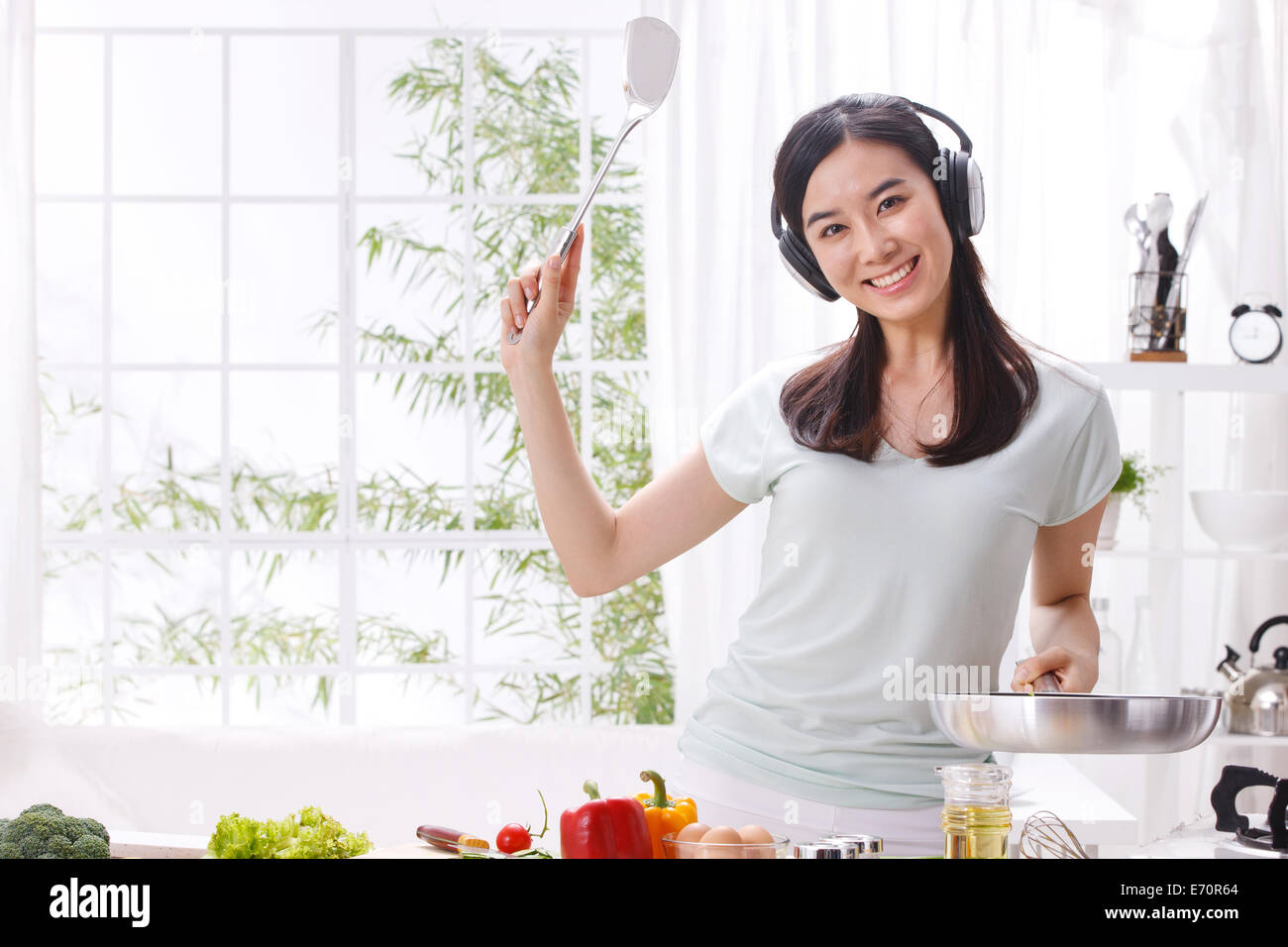Young woman listening to music and cooking in kitchen Stock Photo - Alamy
