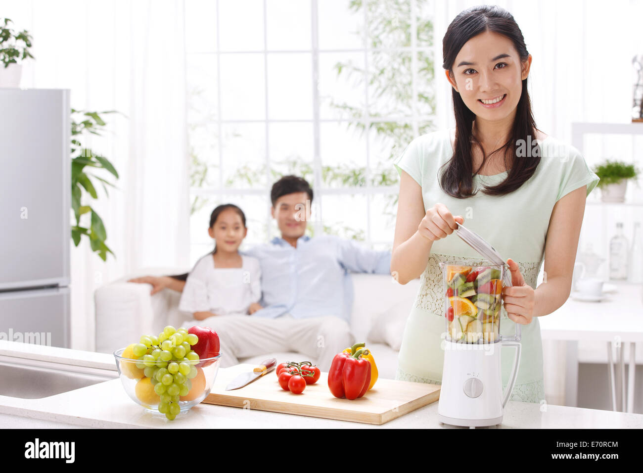 Young woman holding blender with family in kitchen Stock Photo - Alamy
