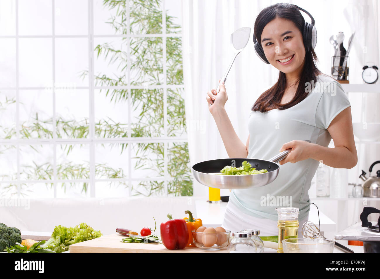 Young woman listening to music and cooking in kitchen Stock Photo - Alamy