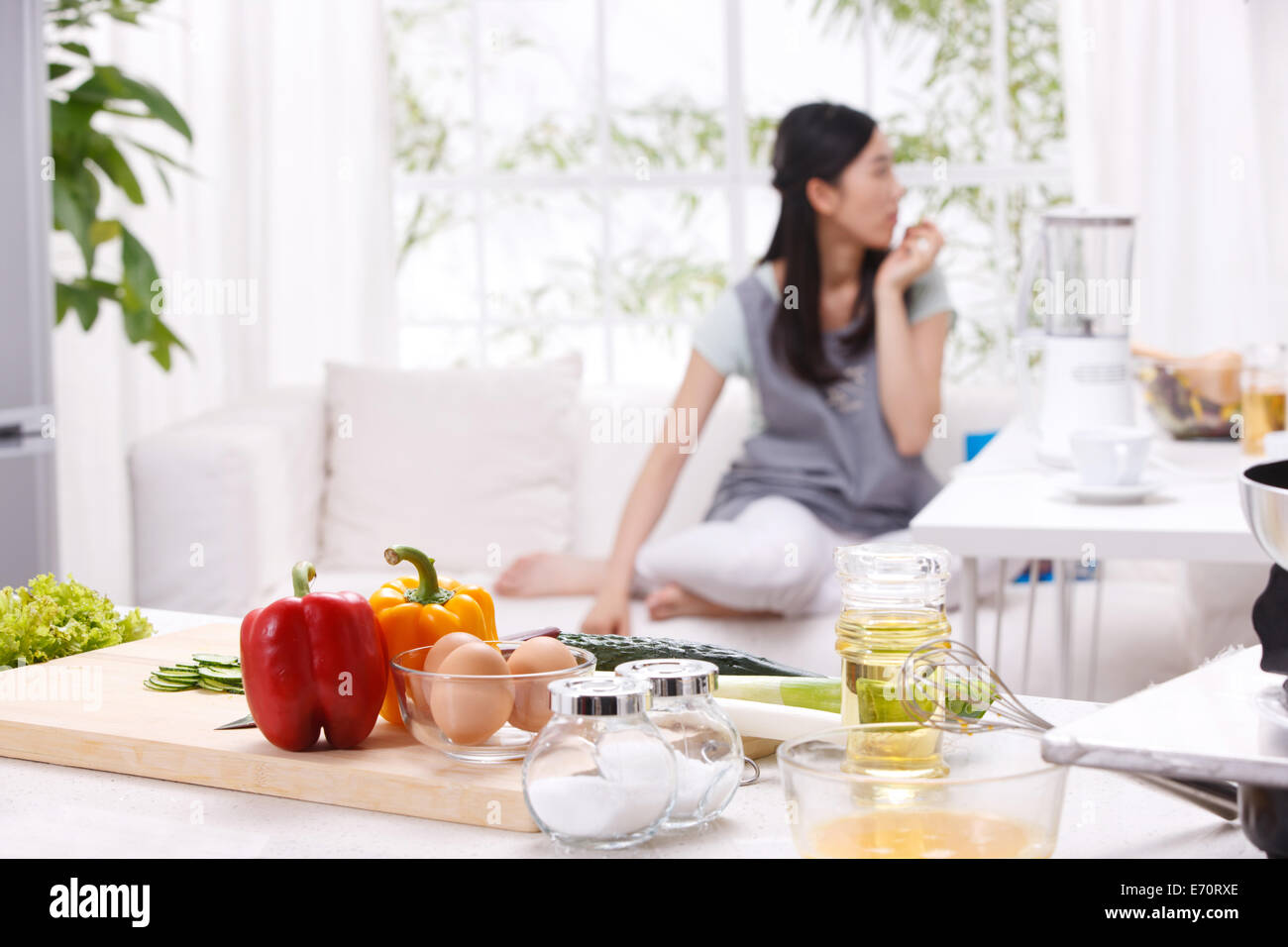 Young woman sitting in kitchen Stock Photo - Alamy