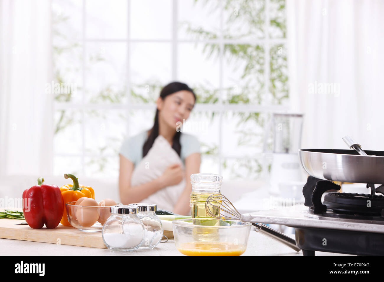 Young woman sitting in kitchen Stock Photo - Alamy